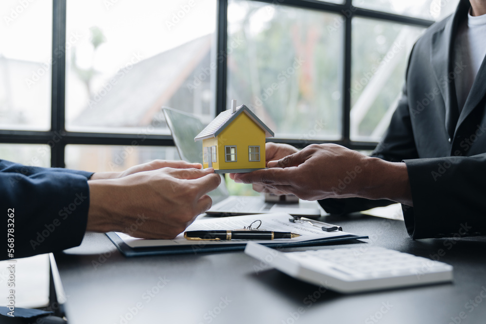 Young Asian real estate agent, and insurance salesman handing over a ...