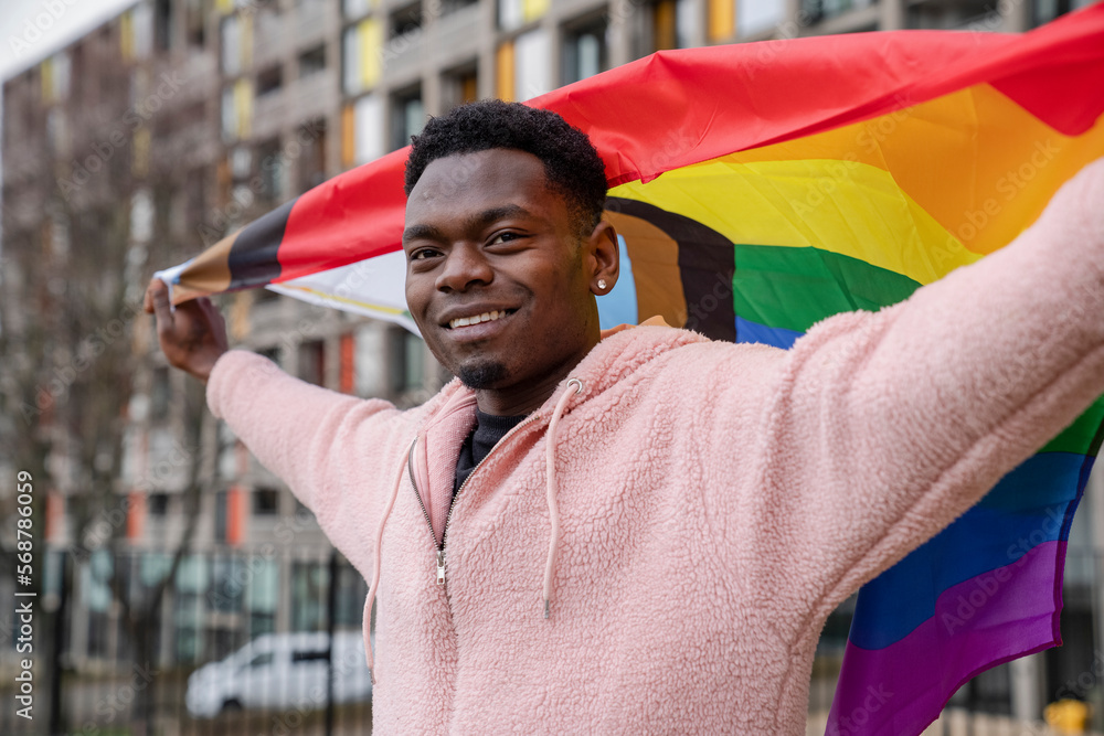 Foto de Smiling young man holding progress pride flag do Stock | Adobe ...