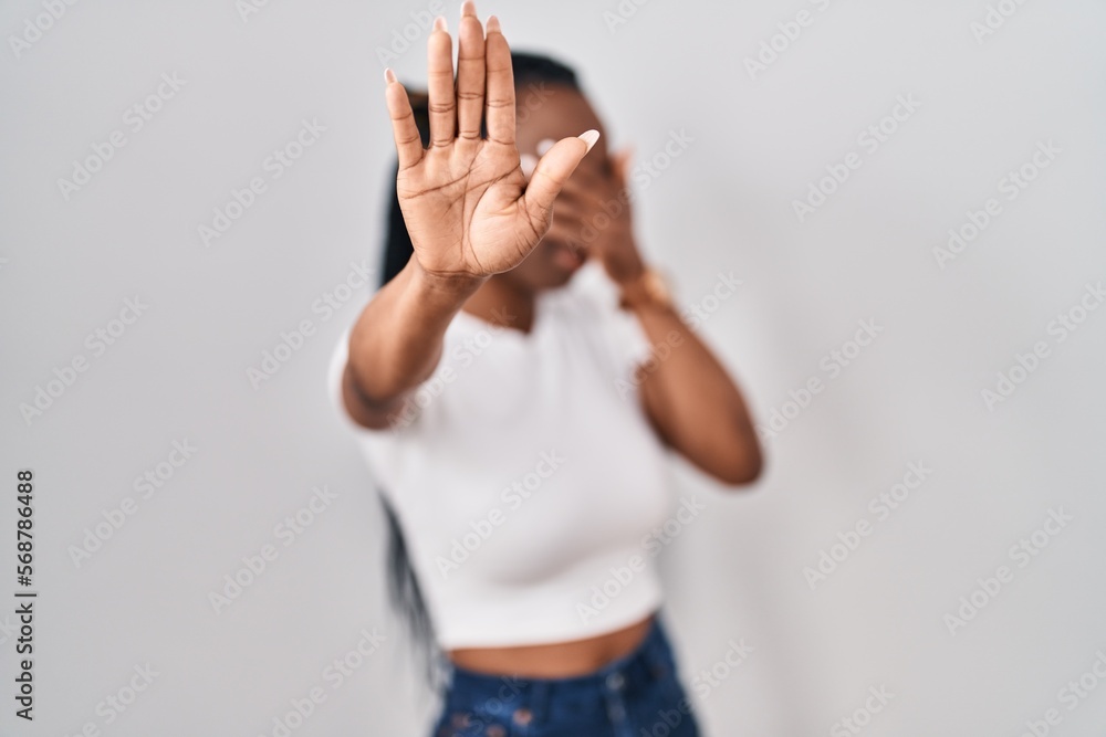 Beautiful black woman standing over isolated background covering eyes ...