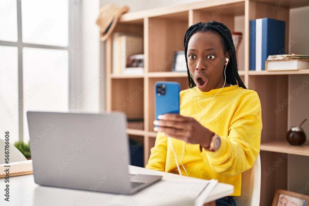 Beautiful black woman doing video call with smartphone scared and ...