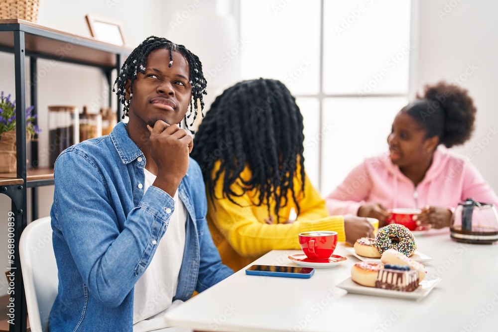 Group of three young black people sitting on a table having coffee ...