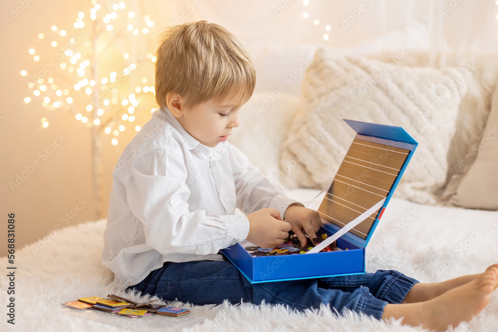Cute little preschool child, playing with alphabet game, learning ...