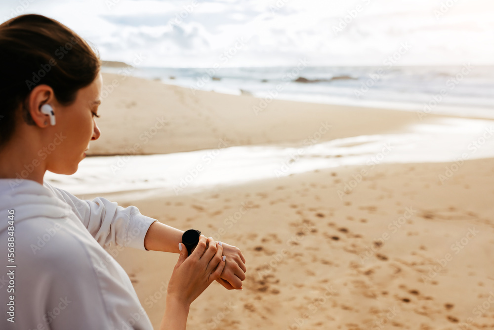 Athletic young woman tracking her outdoor activity, looking at ...
