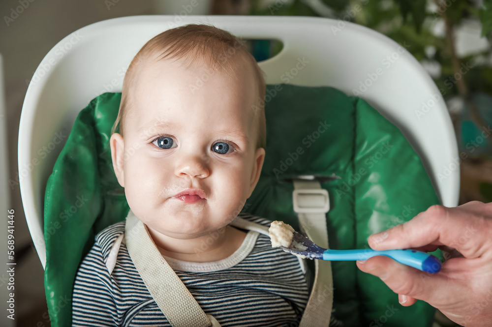 Complementary feeding of child, baby food. The Infant is spoon-fed ...
