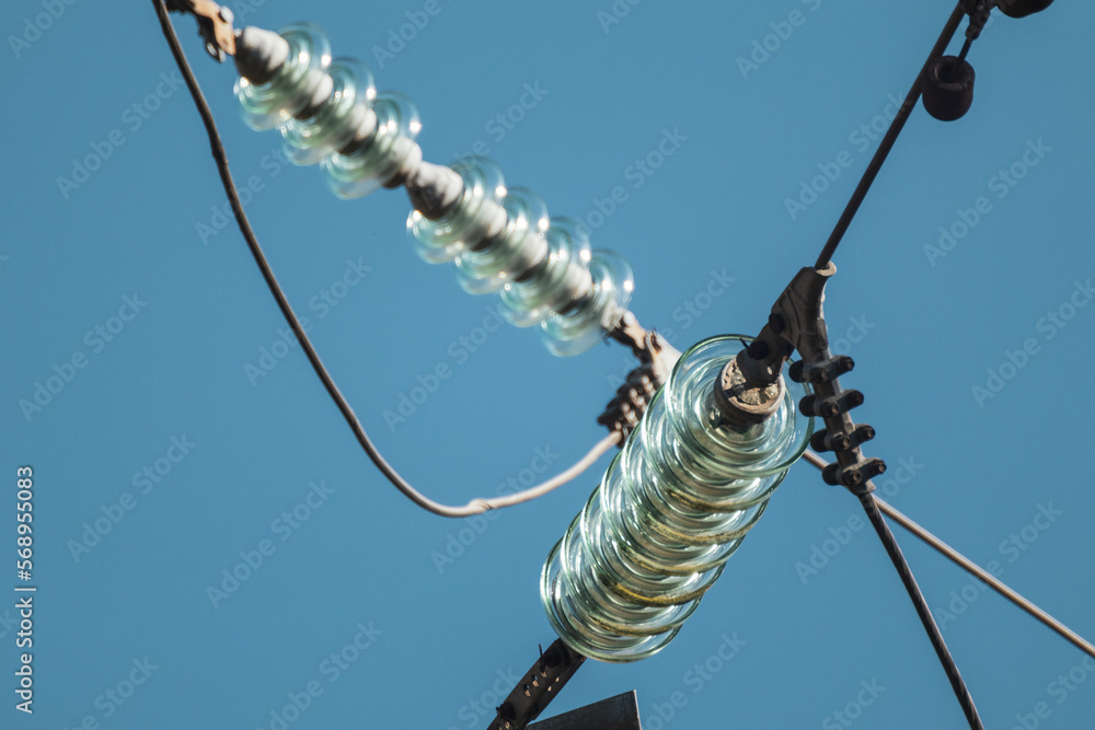 High voltage glass insulators on electric transmission line close-up ...