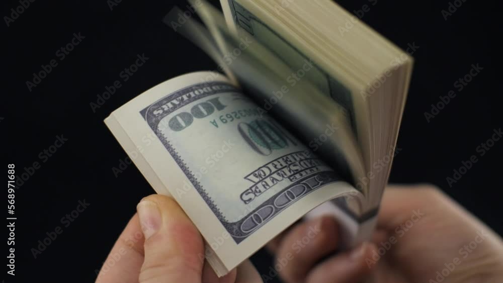 Video Stock On a black background, a hand counts while flipping through ...