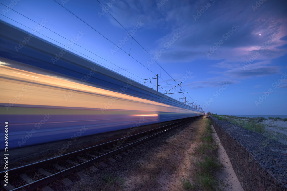 High speed train in motion on the railway station at dusk. Landscape ...