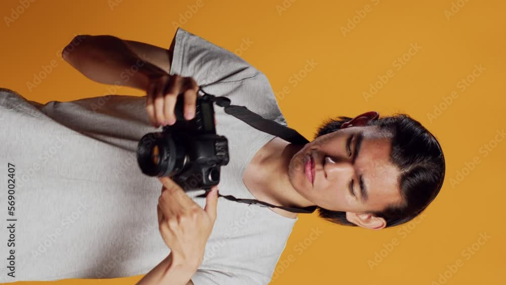 Vertical video: Young professional photographer using dslr camera to ...