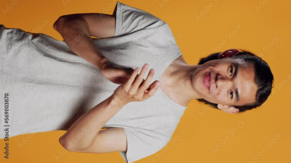 Vertical video: Smiling person clapping hands in studio, laughing and ...