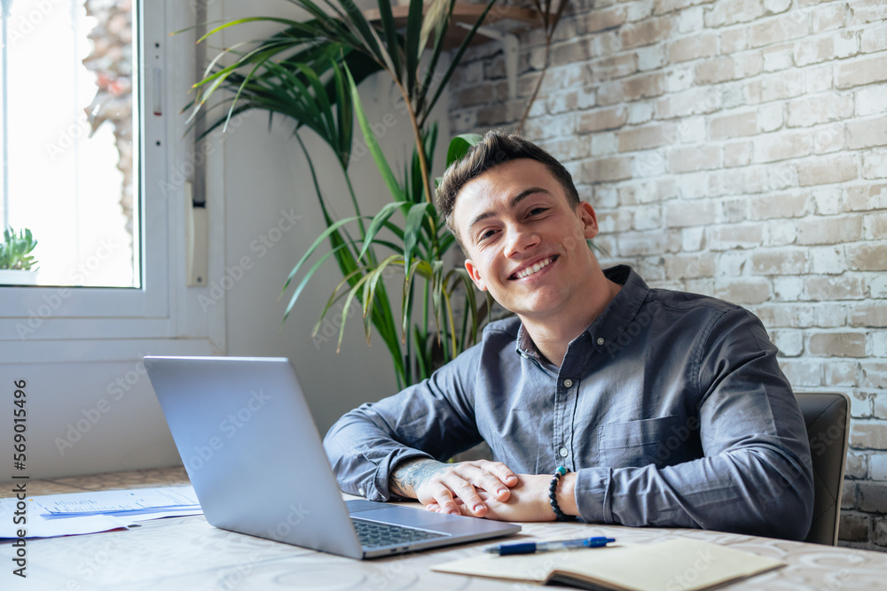Good-looking millennial office employee in glasses sitting at desk in ...