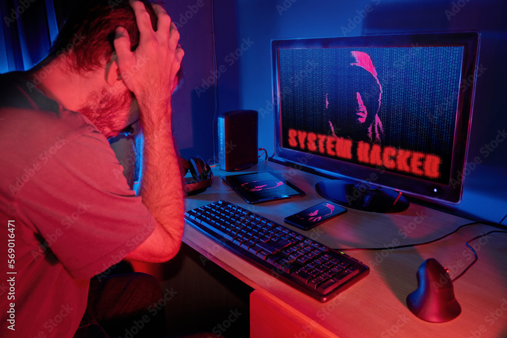 Stressed man holding his head in front of computer showing "System ...