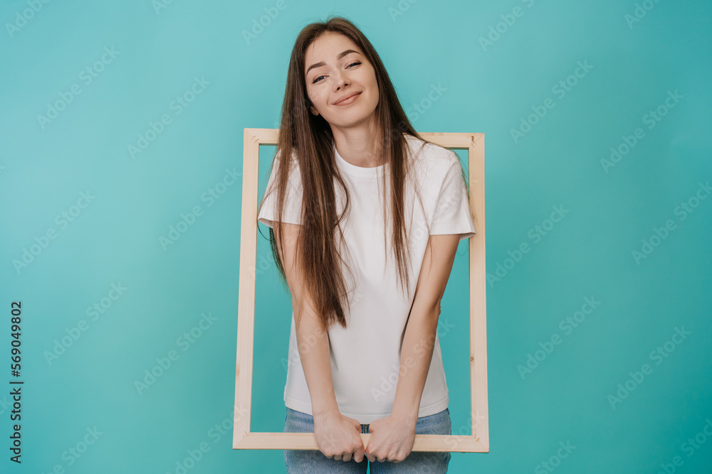 Cute cheerful young woman in white t-shirt and jeans holds frame for ...
