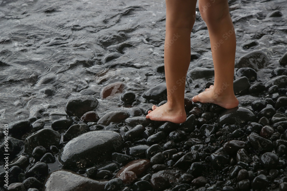 Child's feet barefoot on pebble beach near sea. Walking barefoot ...