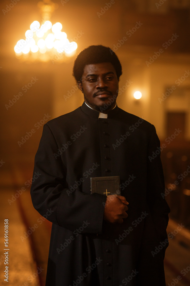 Portrait of a Young Black Priest Holding the Holy Bible in His Hand and ...