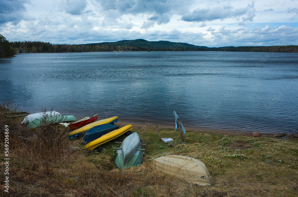 Boats and canoe lie upside down on the shore of the lake Vastra Sveten ...