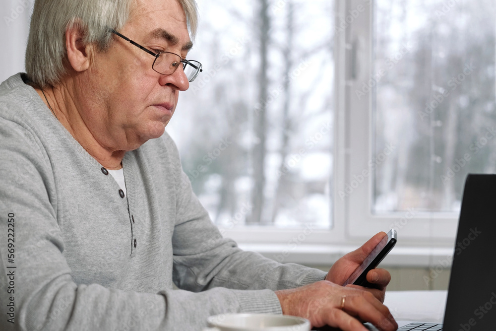 Handsome serious senior man wearing glasses using mobile phone while ...