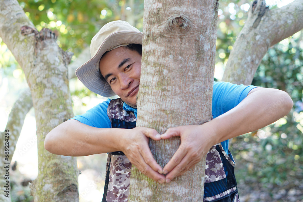 Handsome Asian man botanist hugs trunk of tree in forest, make sign of ...