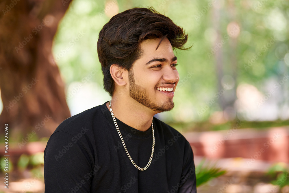 Smiling young indian man candid portrait in black t shirt and silver ...