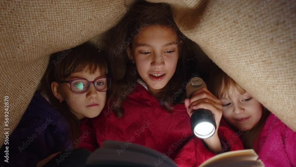 Teen girl and toddler child sisters under blanket plaid covers with ...