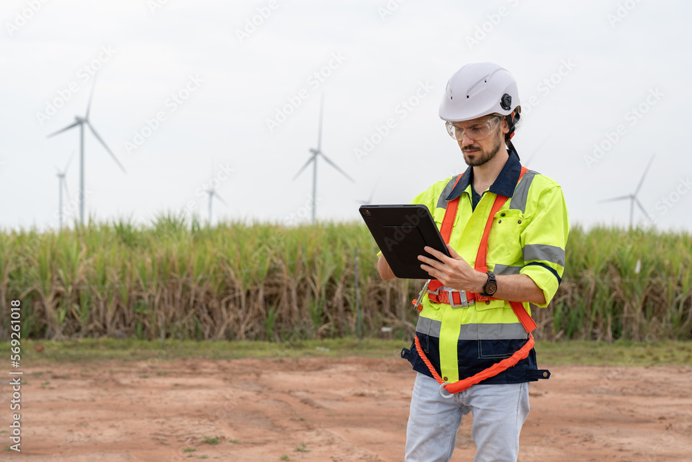 Male engineer windmill wearing uniform and helmet using tablet ...