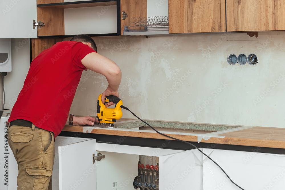 The furniture master installs a modern kitchen in the house, in his ...