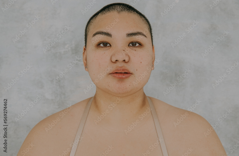 portrait of a plus size filipino woman with a shaved head not smiling ...