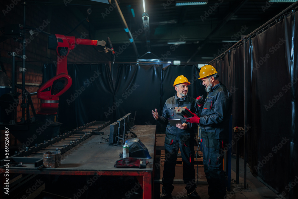 Engineers programming robotic welder. Stock Photo | Adobe Stock