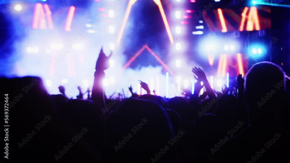 People clap their hands and dance at evening concert with light show ...