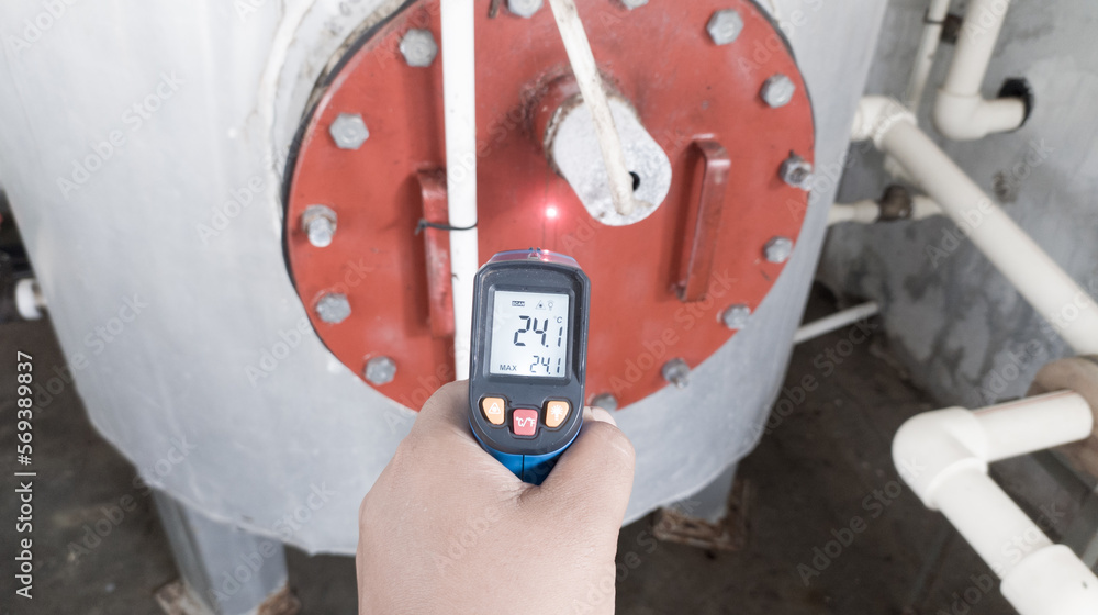 An engineer checking the temperature on area water heater boiler tank ...