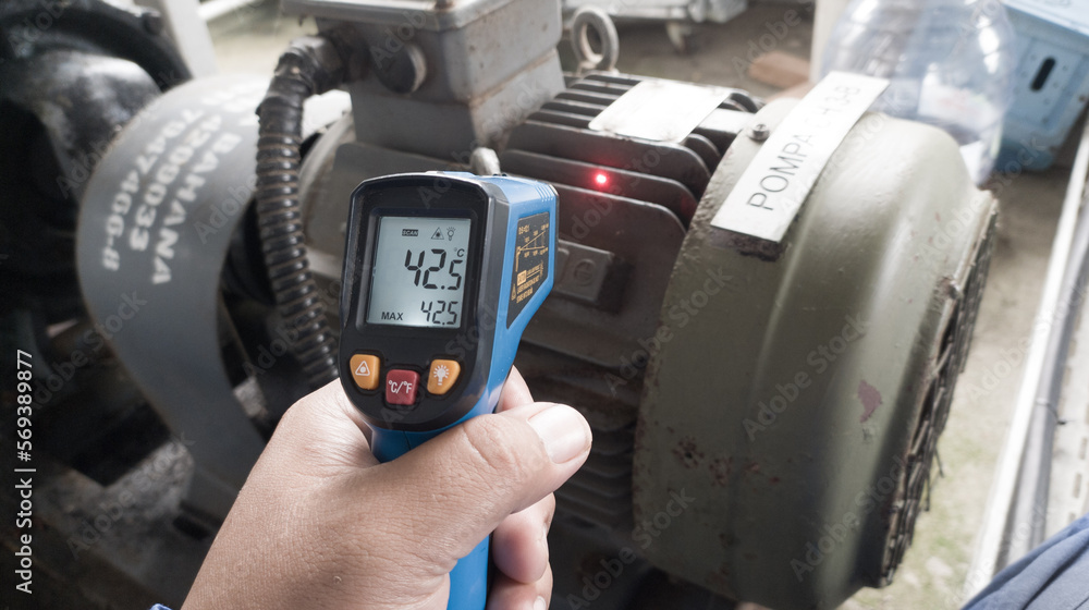 An engineer checking the temperature on an electric motor using an ...