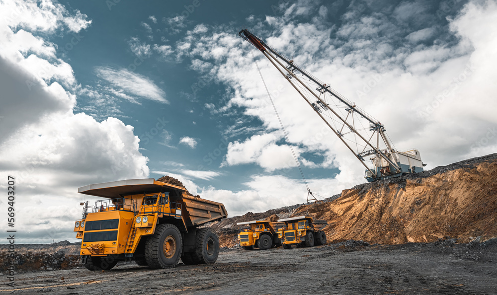 Large quarry dump truck. Big yellow mining truck at work site. Loading coal into body truck ...