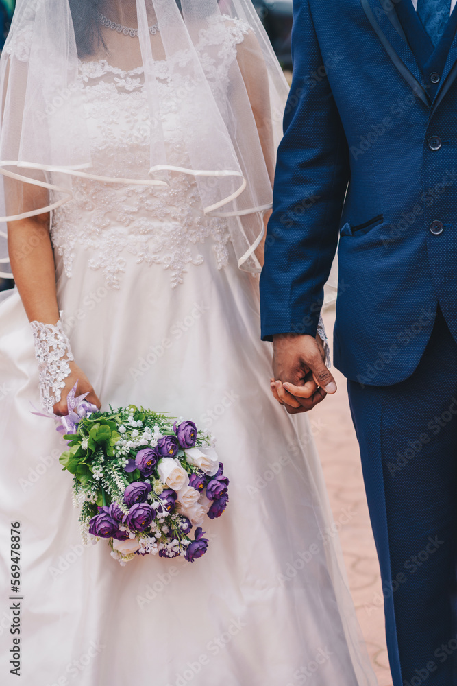 Cropped photo of bride and groom holding hands on wedding day. The ...
