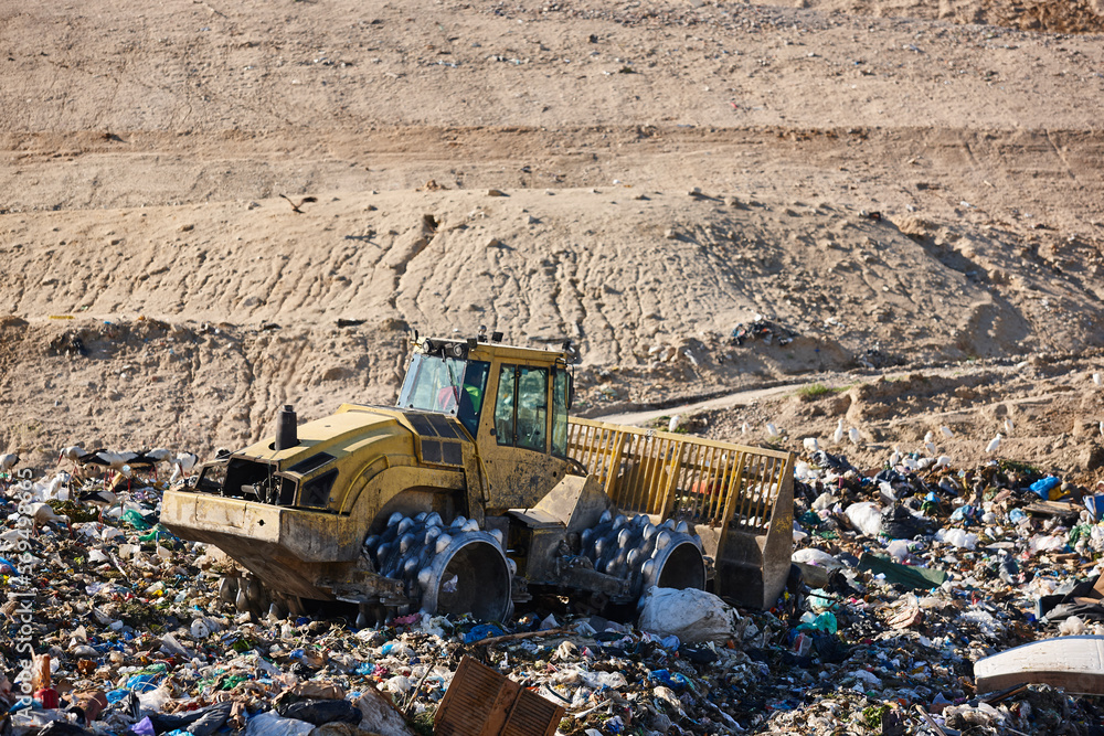 Heavy machinery shredding garbage in an open air landfill. Pollution ...