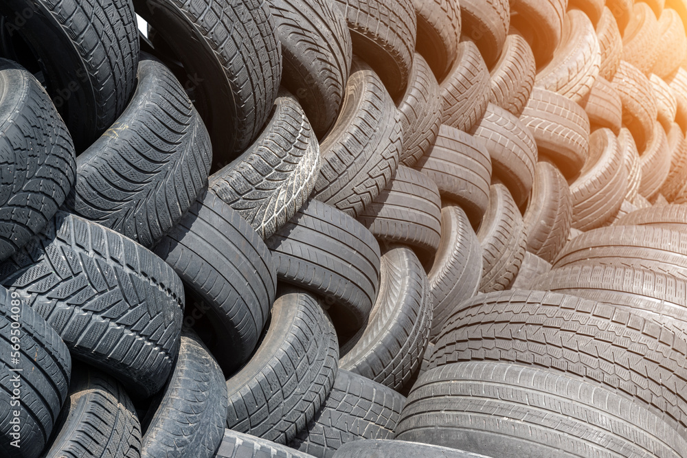Old used weared car and truck wheels tyres pile stacked in rows stored ...