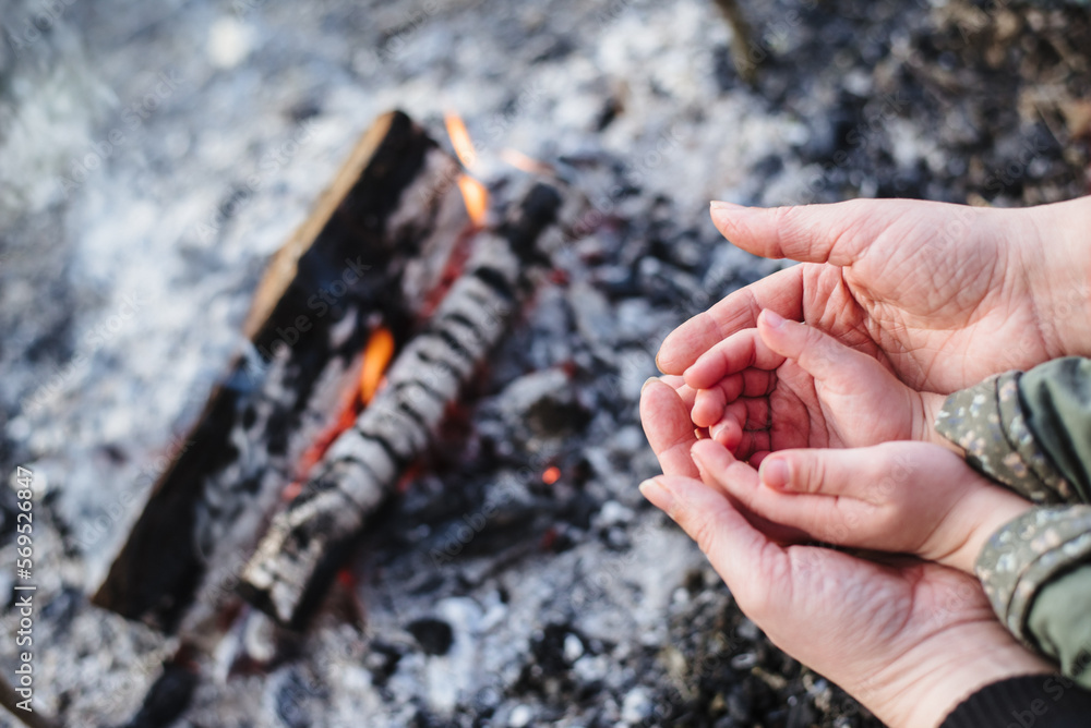 Mom with baby basking by the fire. Close up of baby's hands in mom's ...