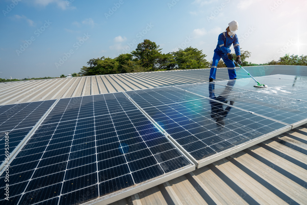Technician using a mop and water to clean the solar panels that are ...