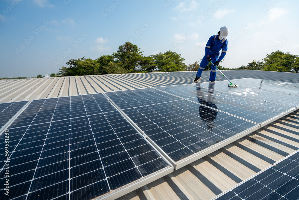 Technician using a mop and water to clean the solar panels that are ...