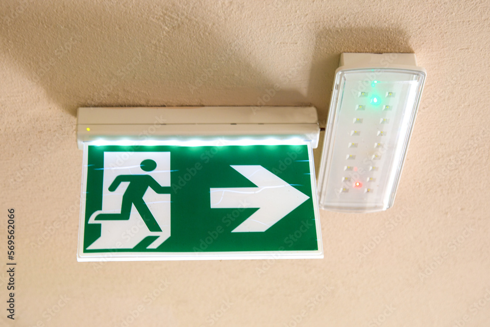 Electrically illuminated emergency exit sign mounted corridor ceiling ...
