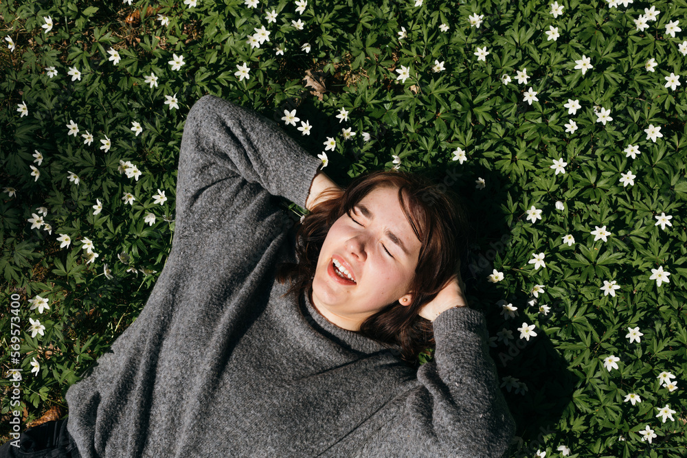 Foto de Spring allergies. A beautiful young woman sneezing amidst a blooming flowers ...