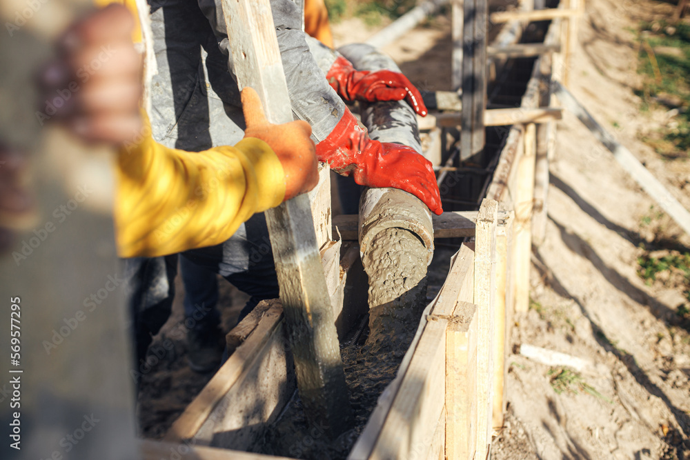 Workers pouring concrete in formwork for foundation. Construction site ...