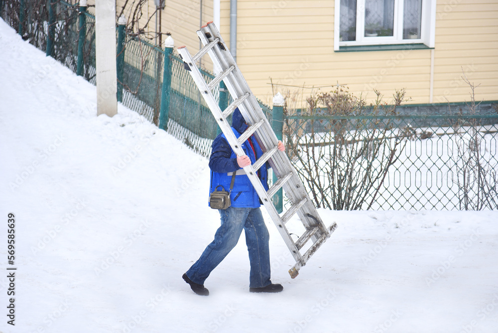 Foto de Man carries a folding ladder down the street to install and ...