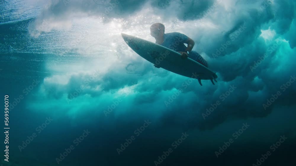 Surfer underwater. Man dives under the wave with surfboard to pass the ...