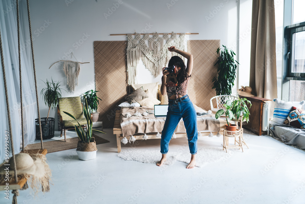 Young lady standing barefoot with hand raised and looking through ...