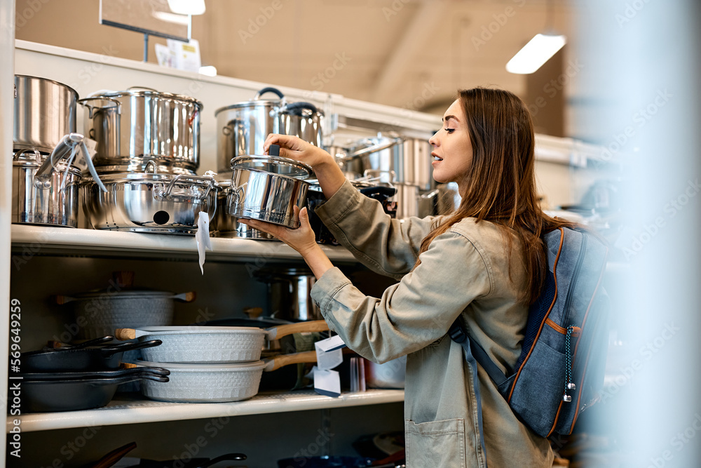 Happy woman chooses new cooking pan while shopping kitchen utensils at ...