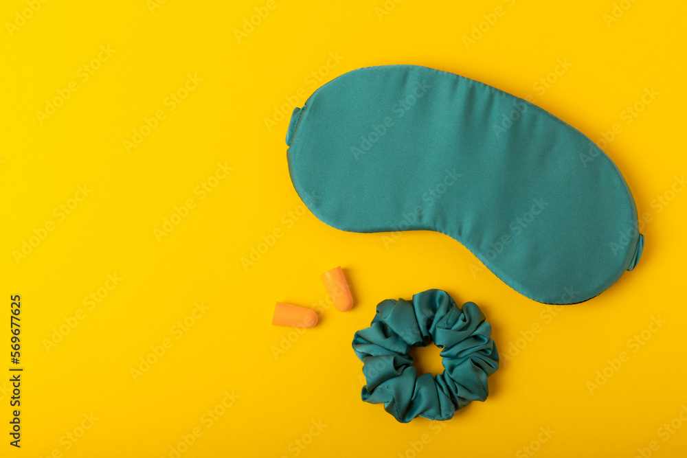 Sleep mask, ear plugs and hair tie on a yellow background. The concept ...