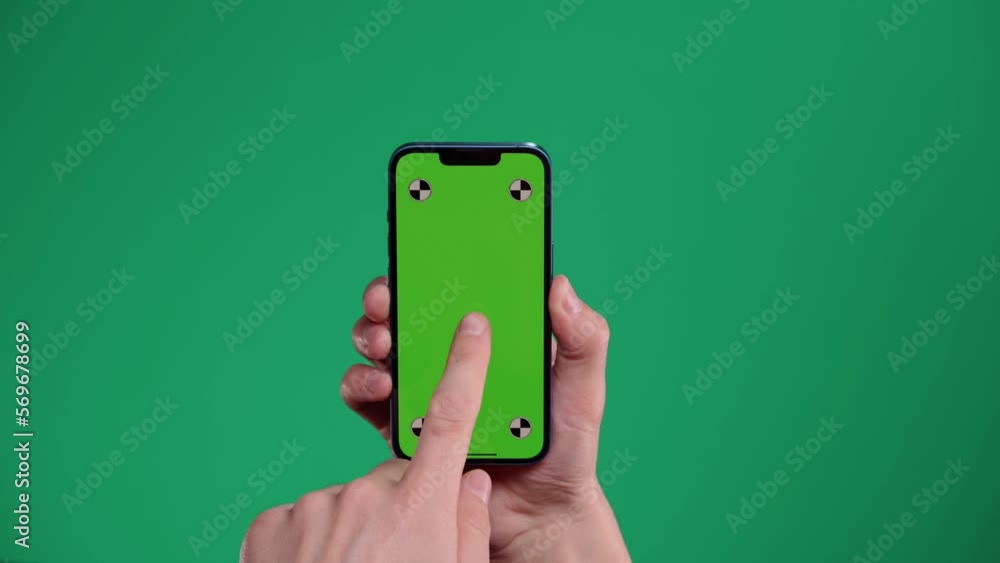 Man's Hand Holding Mobile Phone in Vertical Mode with Green Mock-up Screen On Green Chroma Key ...