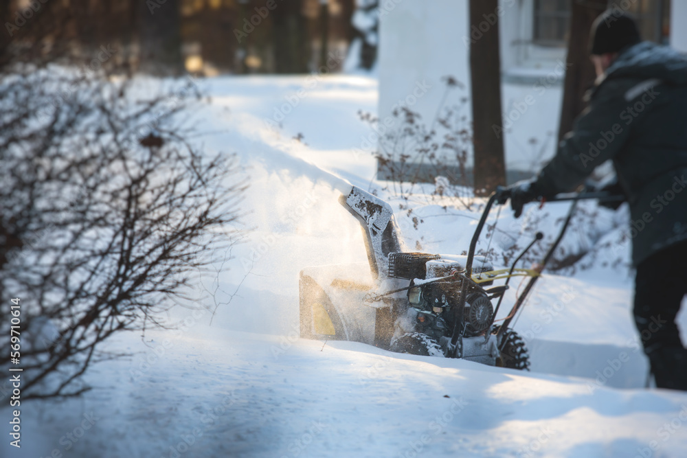 Foto de Process of removing snow with portable blower machine, worker dressed in overall ...