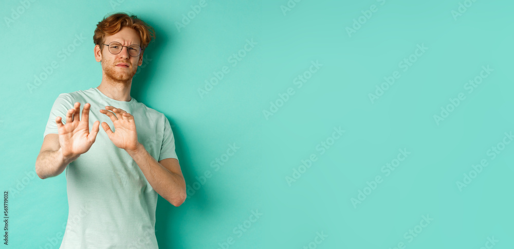 Reluctant redhead man in glasses raising hands in refusal gesture, step ...