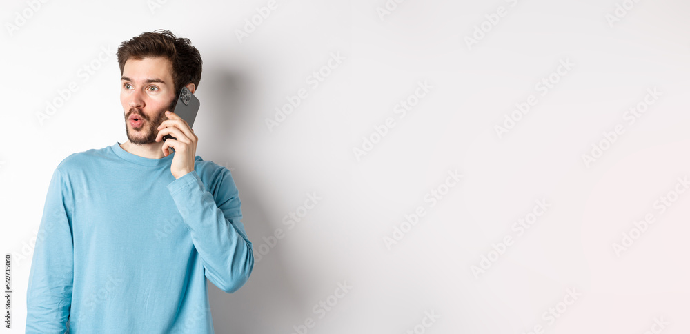 Technology concept. Intrigued young man looking left impressed, talking ...