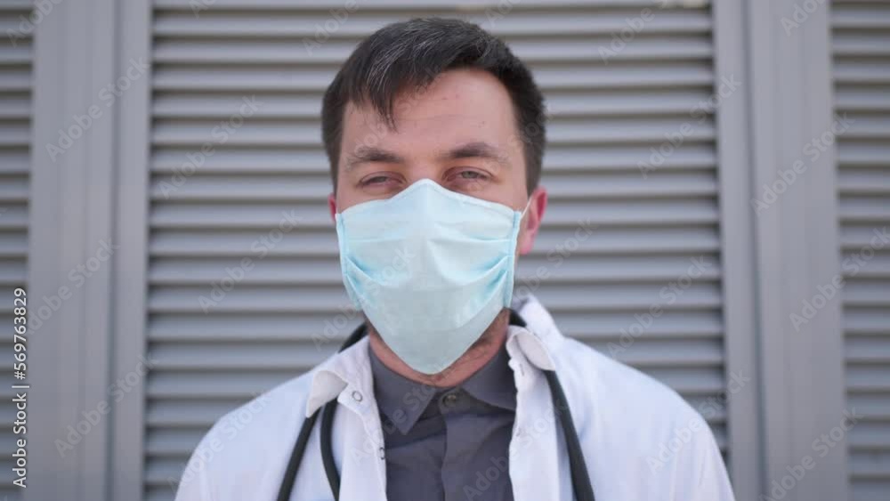Serious doctor removing medical mask from face. Tired young physician ...
